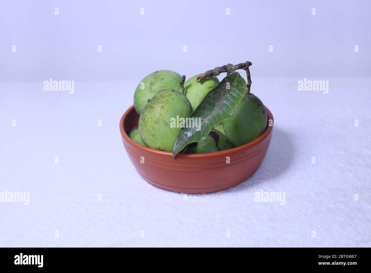 green local fresh mangoes in earthenware on white background Stock ...