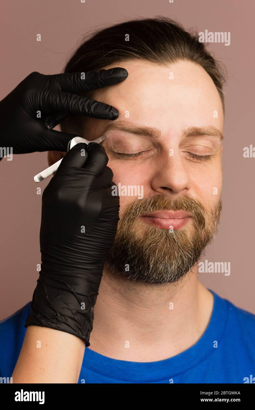 Professional barber doing threading procedure and correcting shape of ...