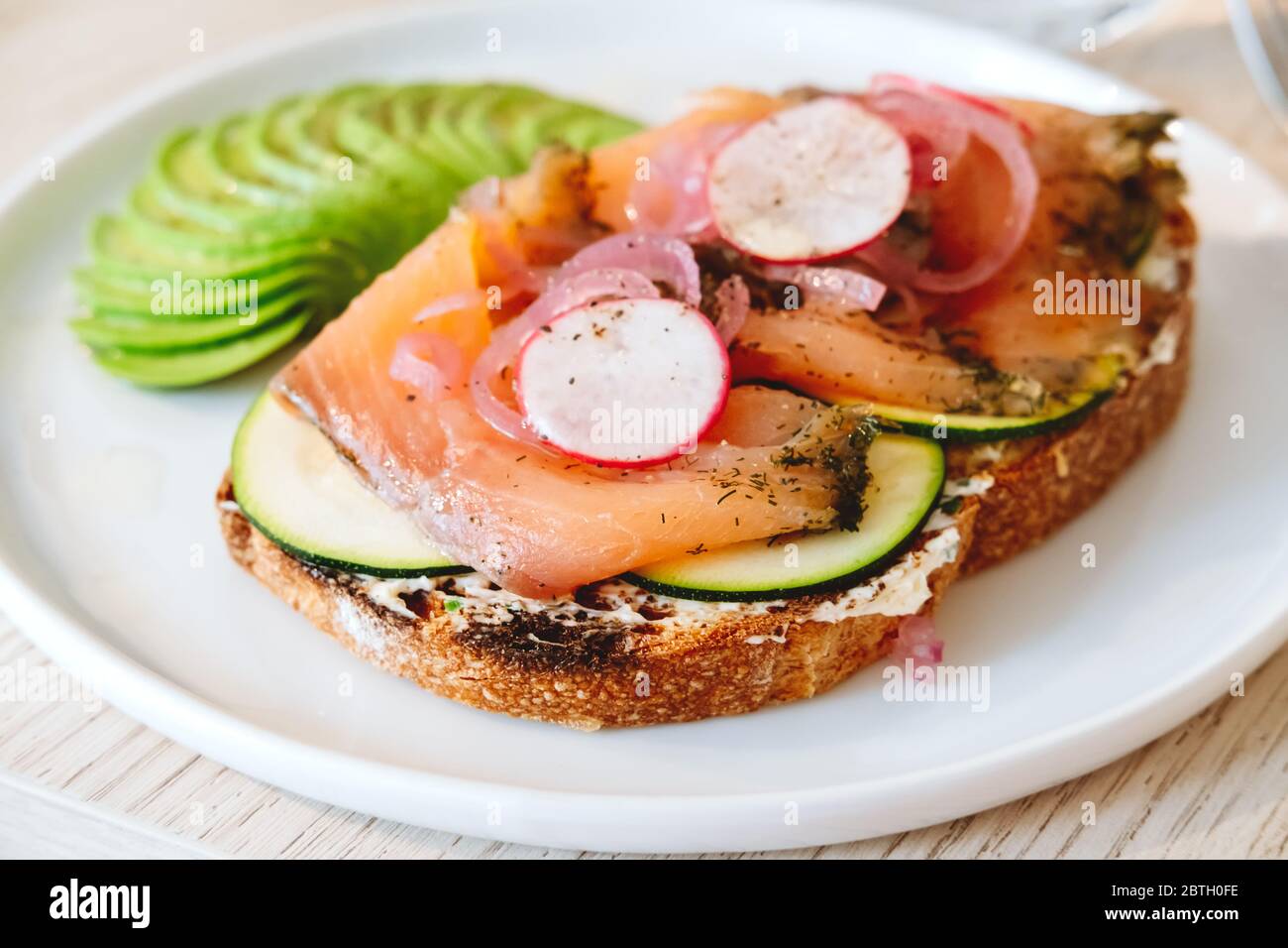 Salmon toast with avocado and vegs in the modern cafe. Fancy cafe and ...