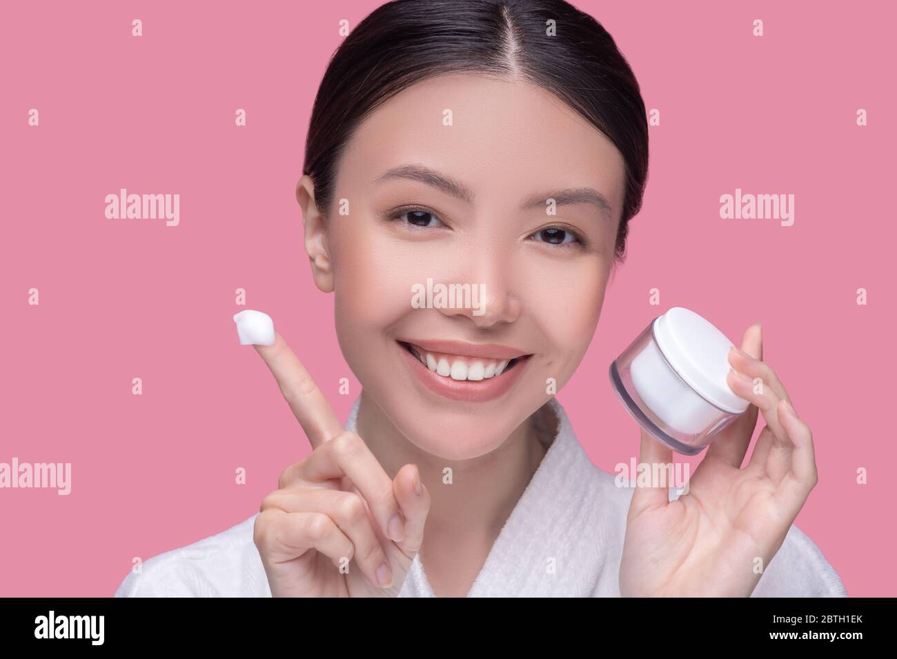 Pretty asian girl taking cream from a jar and looking pleased Stock ...