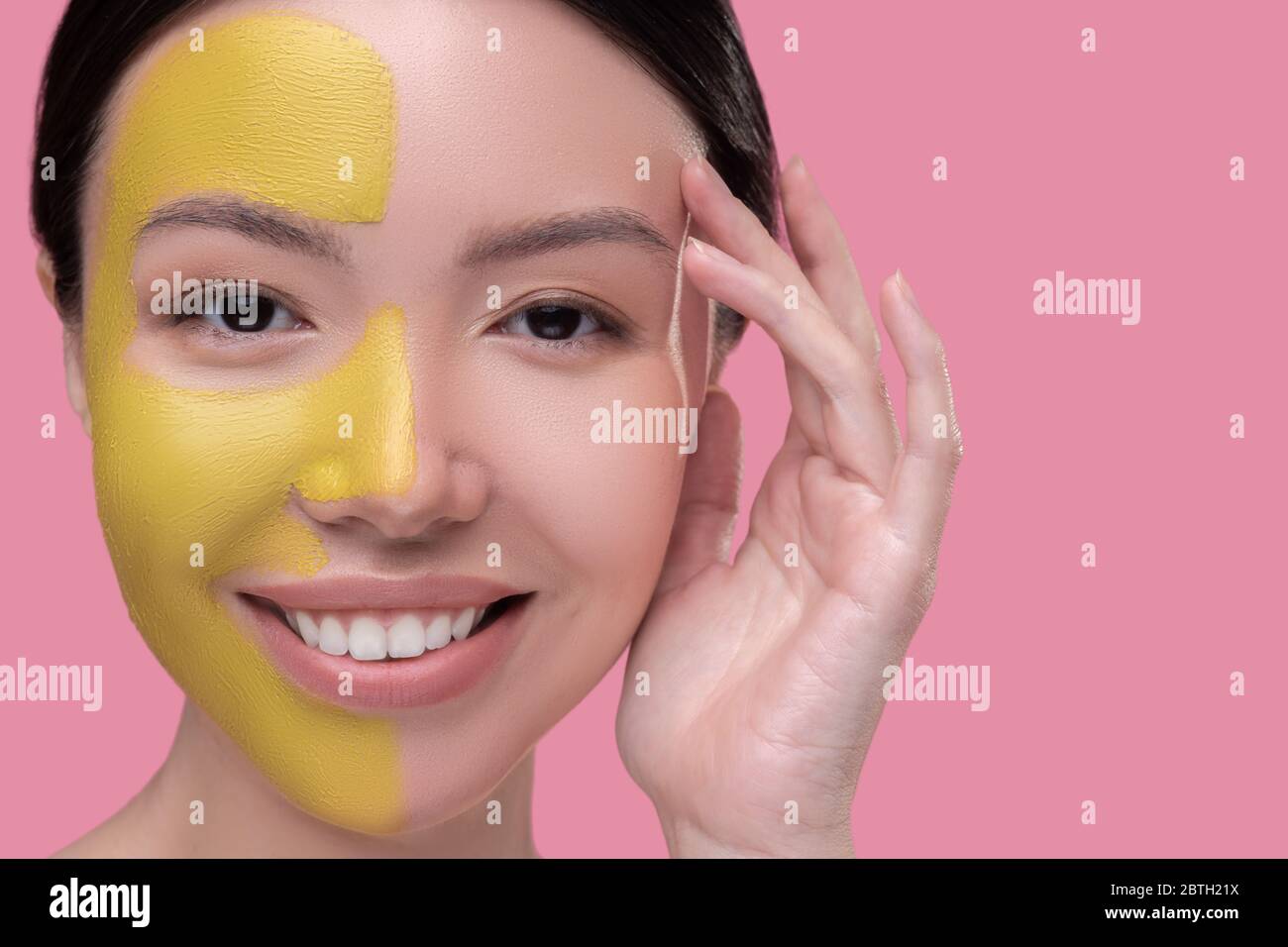 Dark-haired pretty asian girl having facial mask and looking enjoyed ...