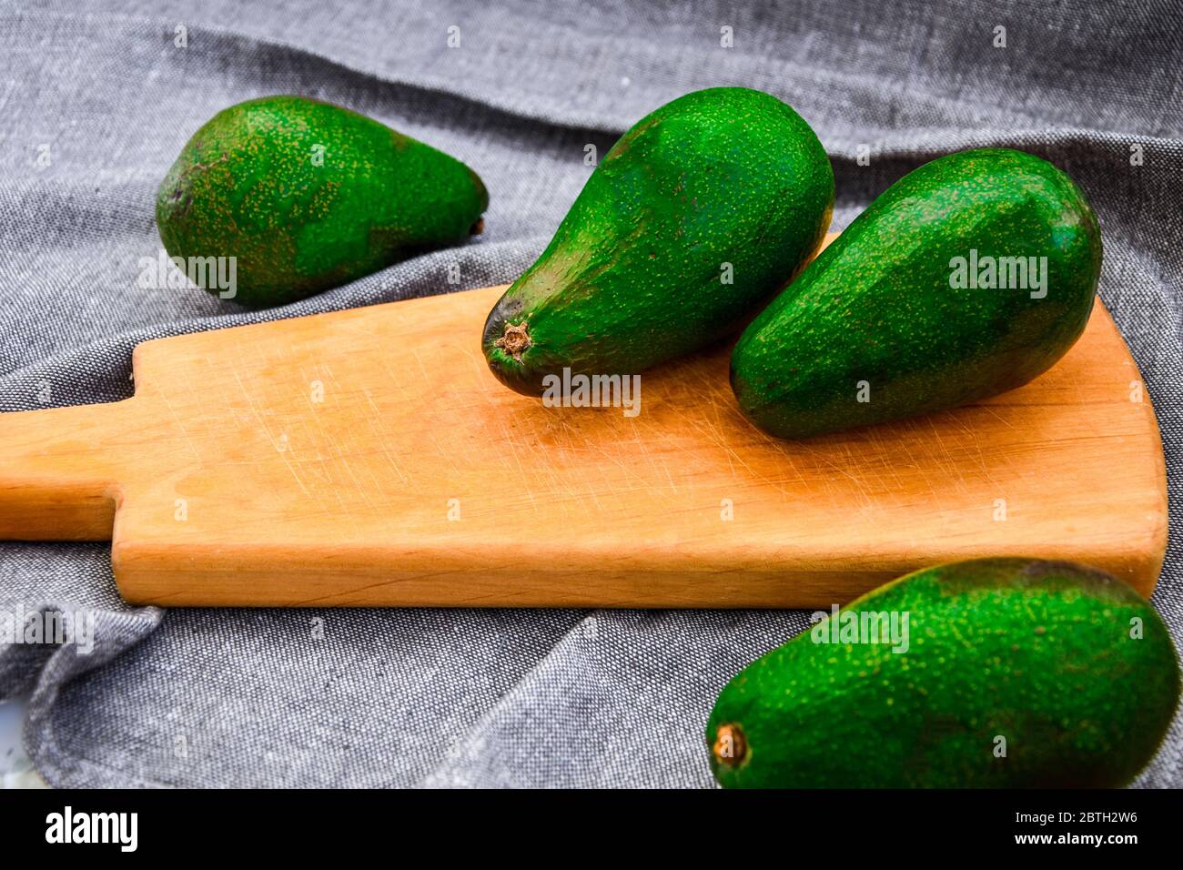 whole green avocado on the wooden tray and grey kitchen towel Stock ...