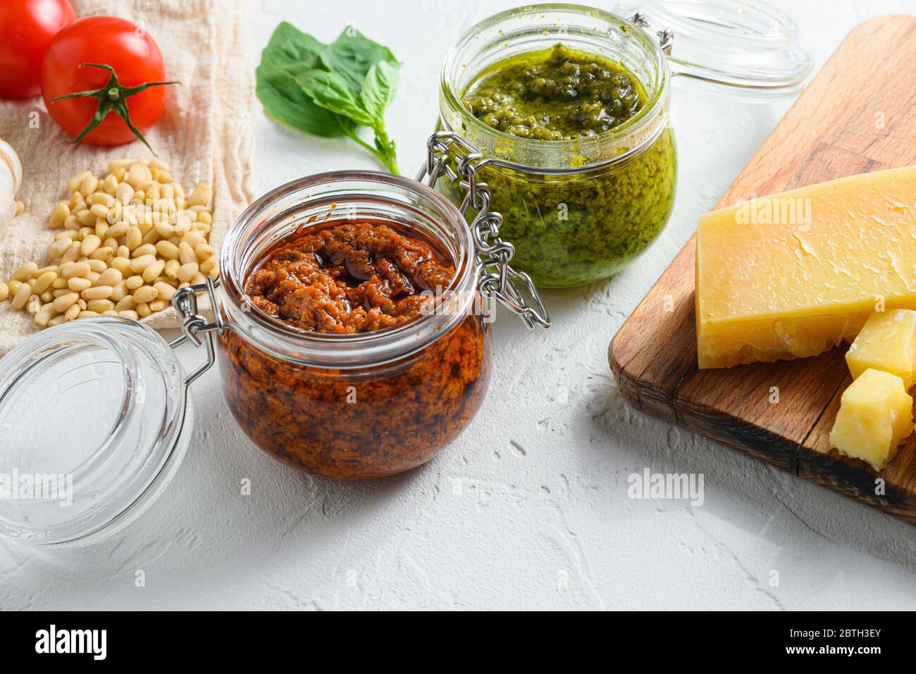 Glass jars with red and green pesto and cooking ingredients Parmesan ...