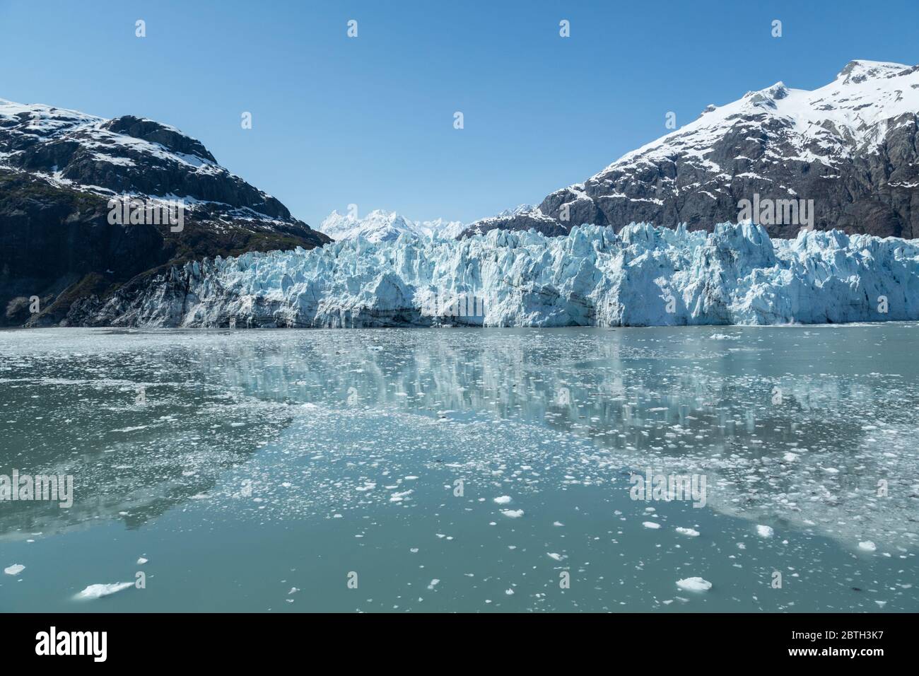 A glacier and mountains reflect in the waters of Alaska's Glacier Bay ...