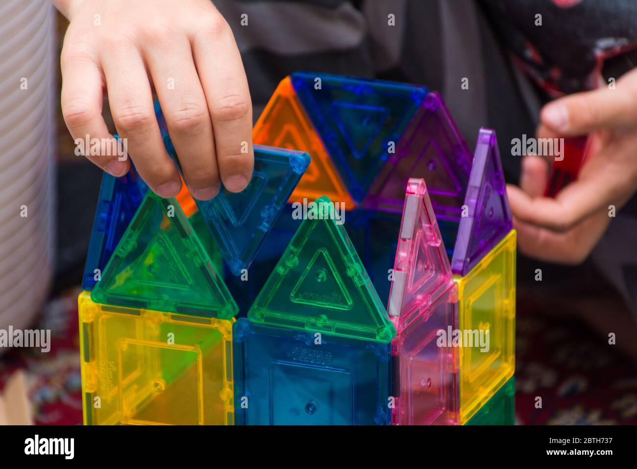 Young child building geometric magnetic shapes into a creative building ...