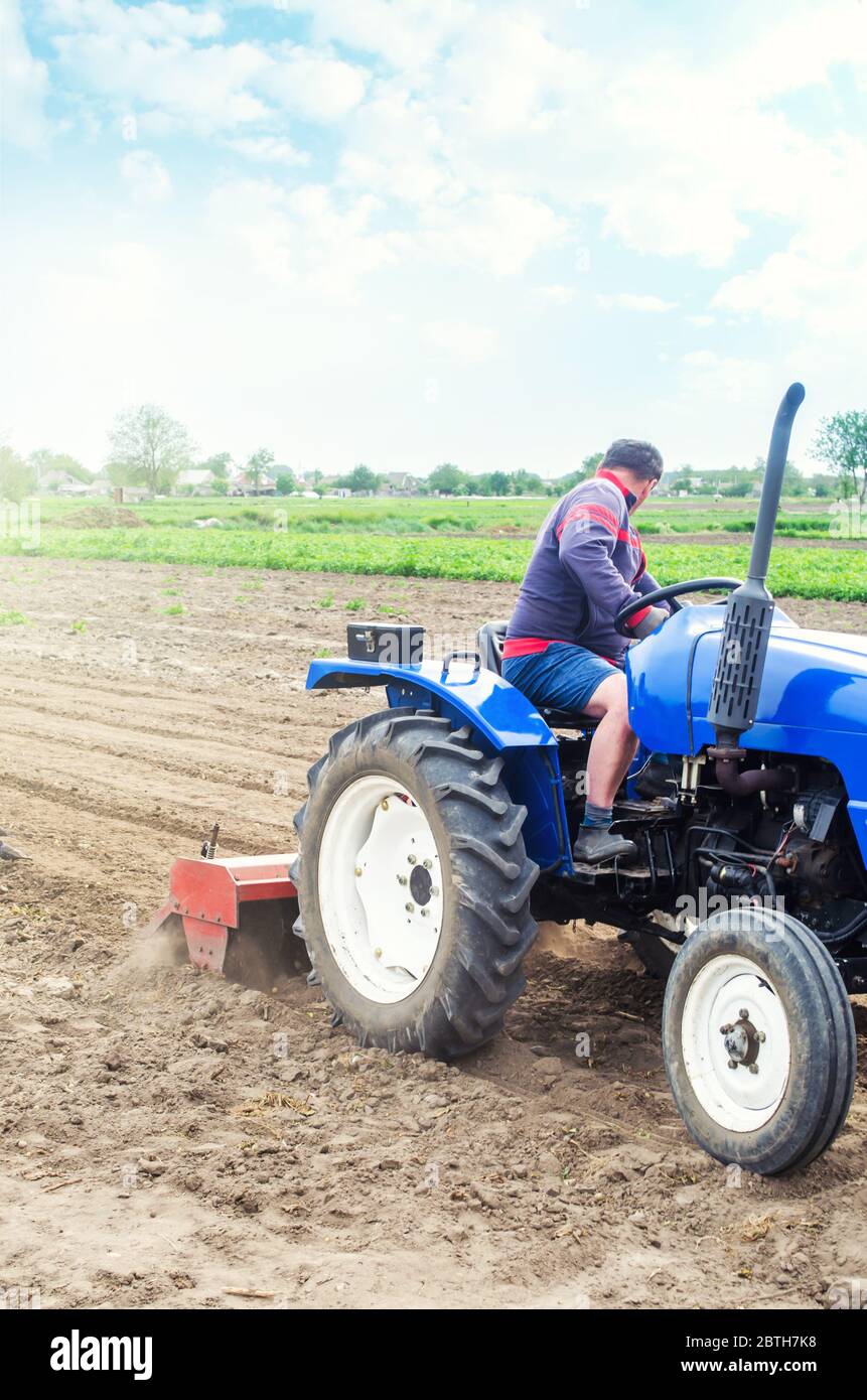 A farmer on a tractor cultivates a farm field. Soil milling, crumbling ...