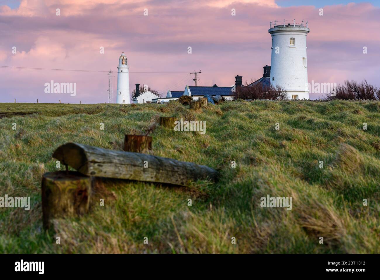 Two lighthouses, set in a rural location, with wooden posts leading the ...
