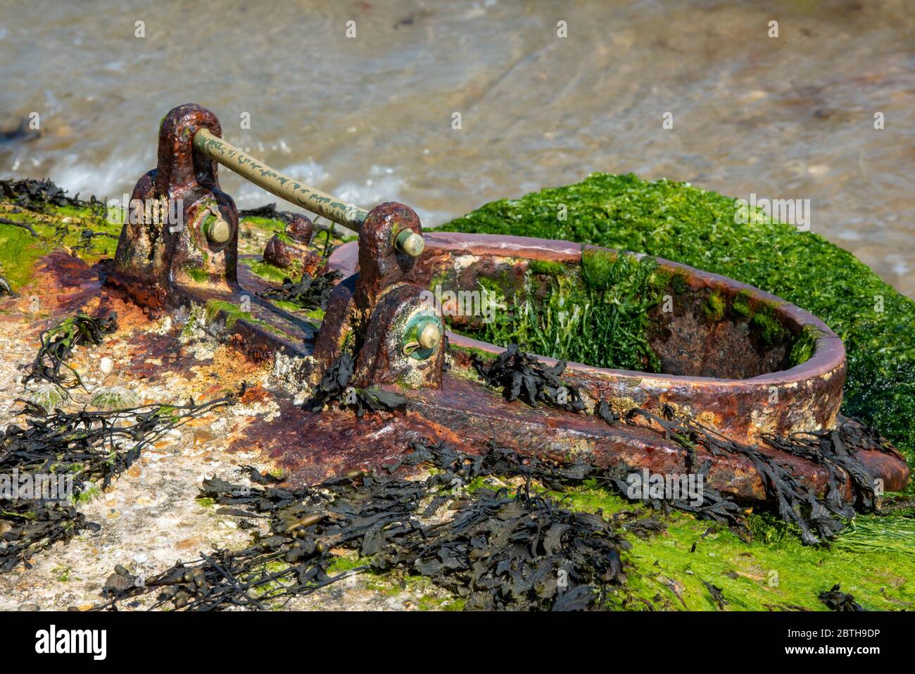 a rusty old corroded porthole on a beach at the seashore showing severe ...