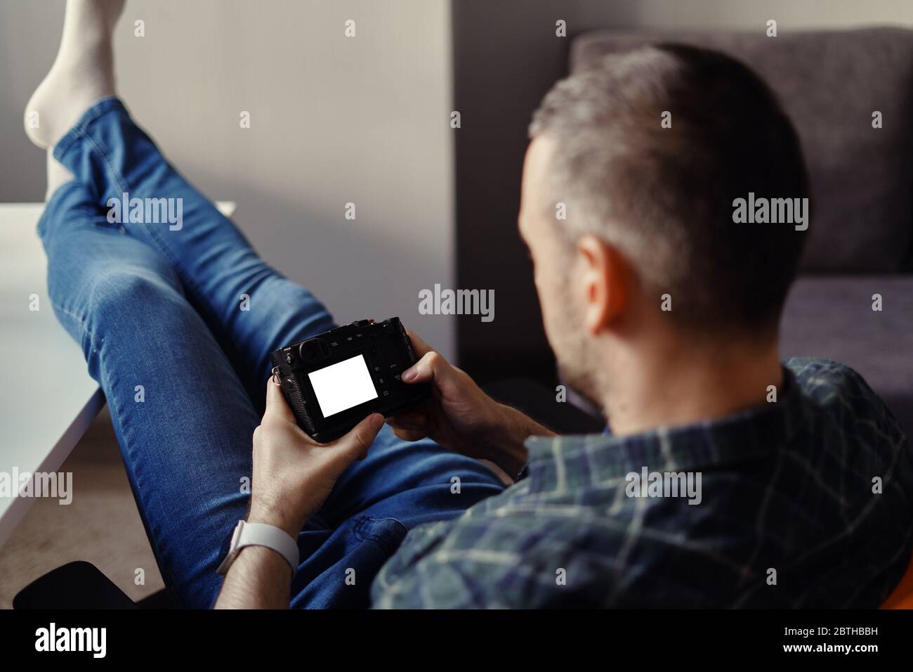 Photographer wathing blank camera display while resting, holding his ...