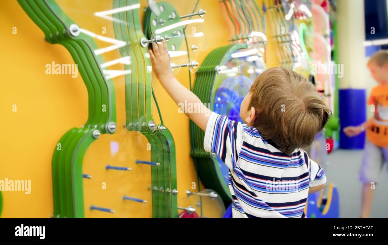Cute little boy playing with educational mechanism in museum of science ...