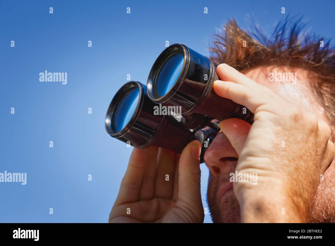 Outdoor type man looking through binoculars Stock Photo - Alamy