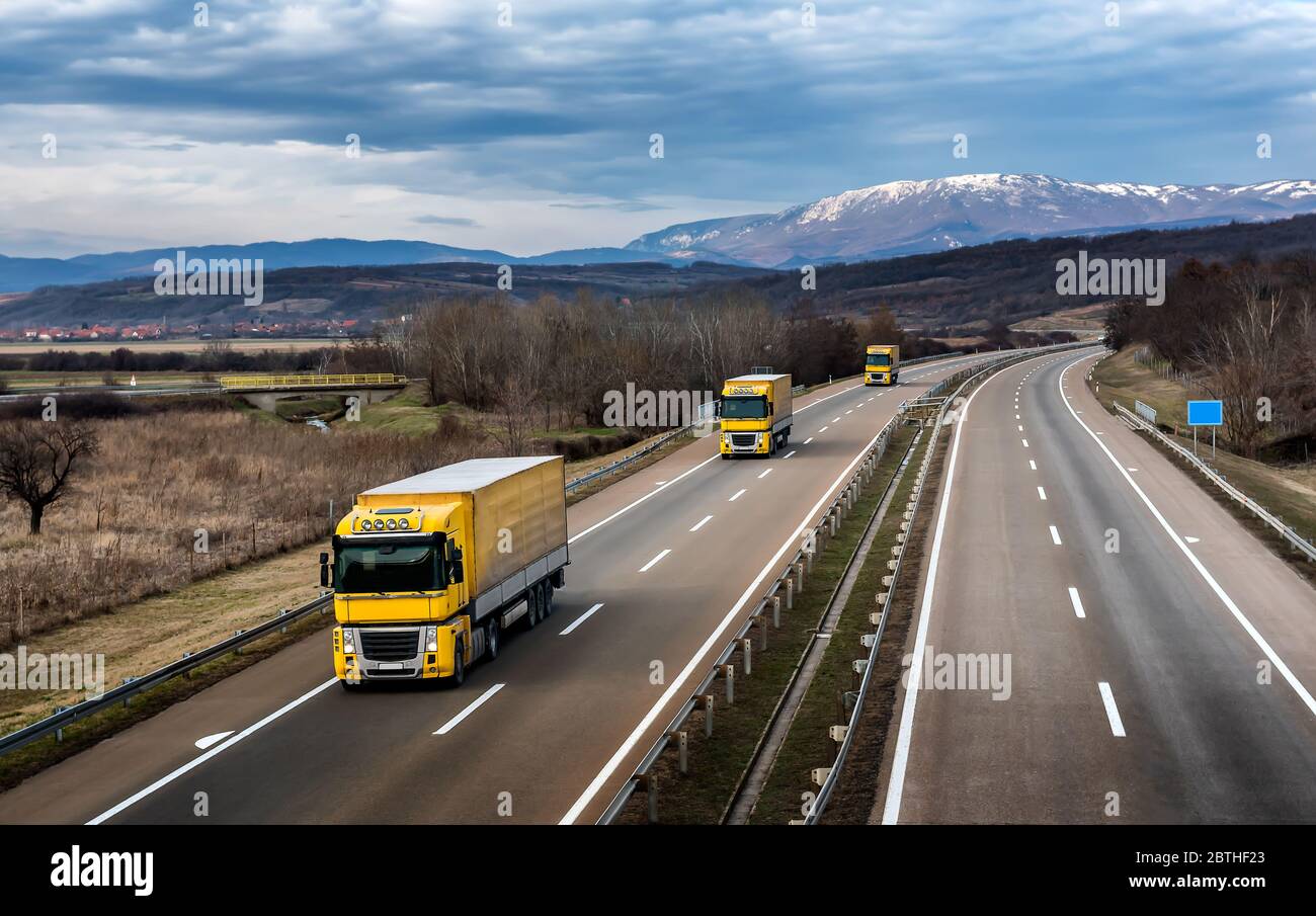 Fleet of Yellow Trucks in line as a convoy at a rural countryside ...