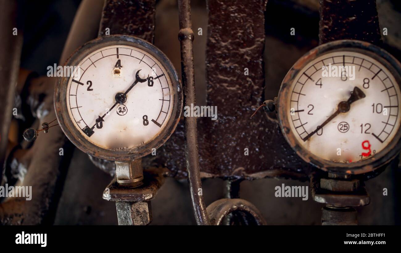 Closeup image of two rusty manometers with analog dials connected to ...