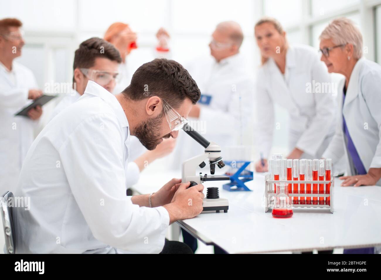 smiling scientist sitting at a laboratory table Stock Photo - Alamy