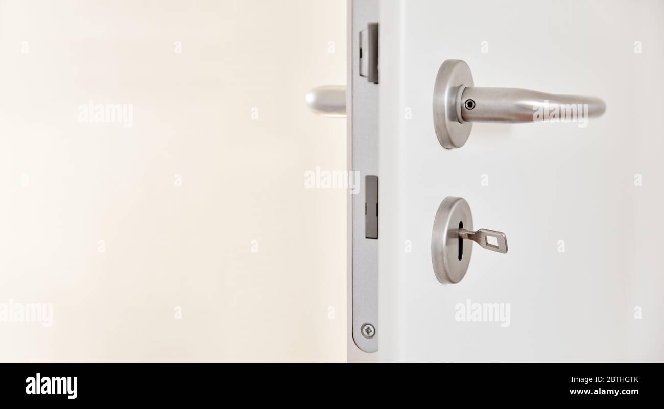 White room door with handle and key in the door lock Stock Photo - Alamy