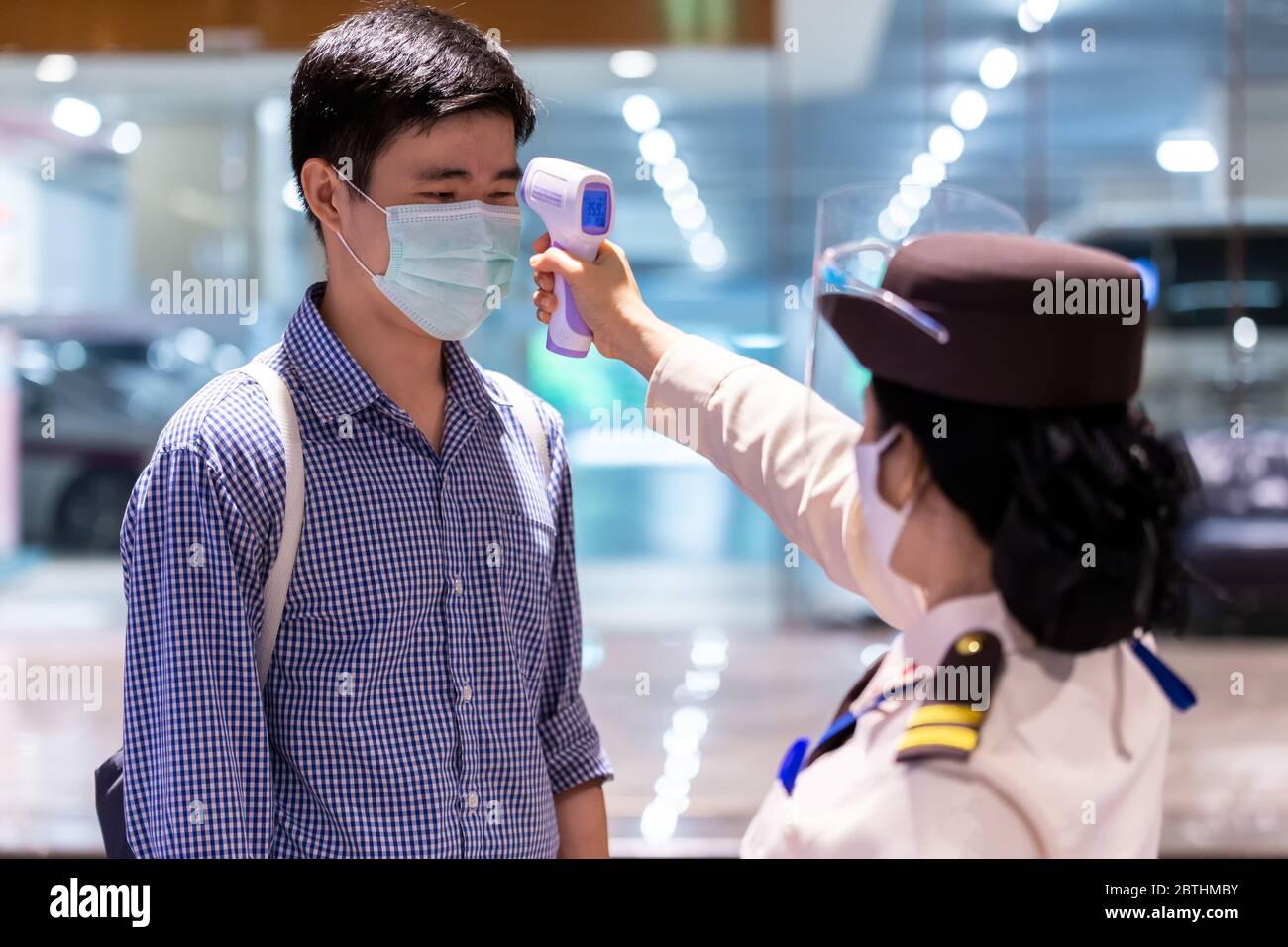 Security guard using infrared thermometer to measure body temperature ...