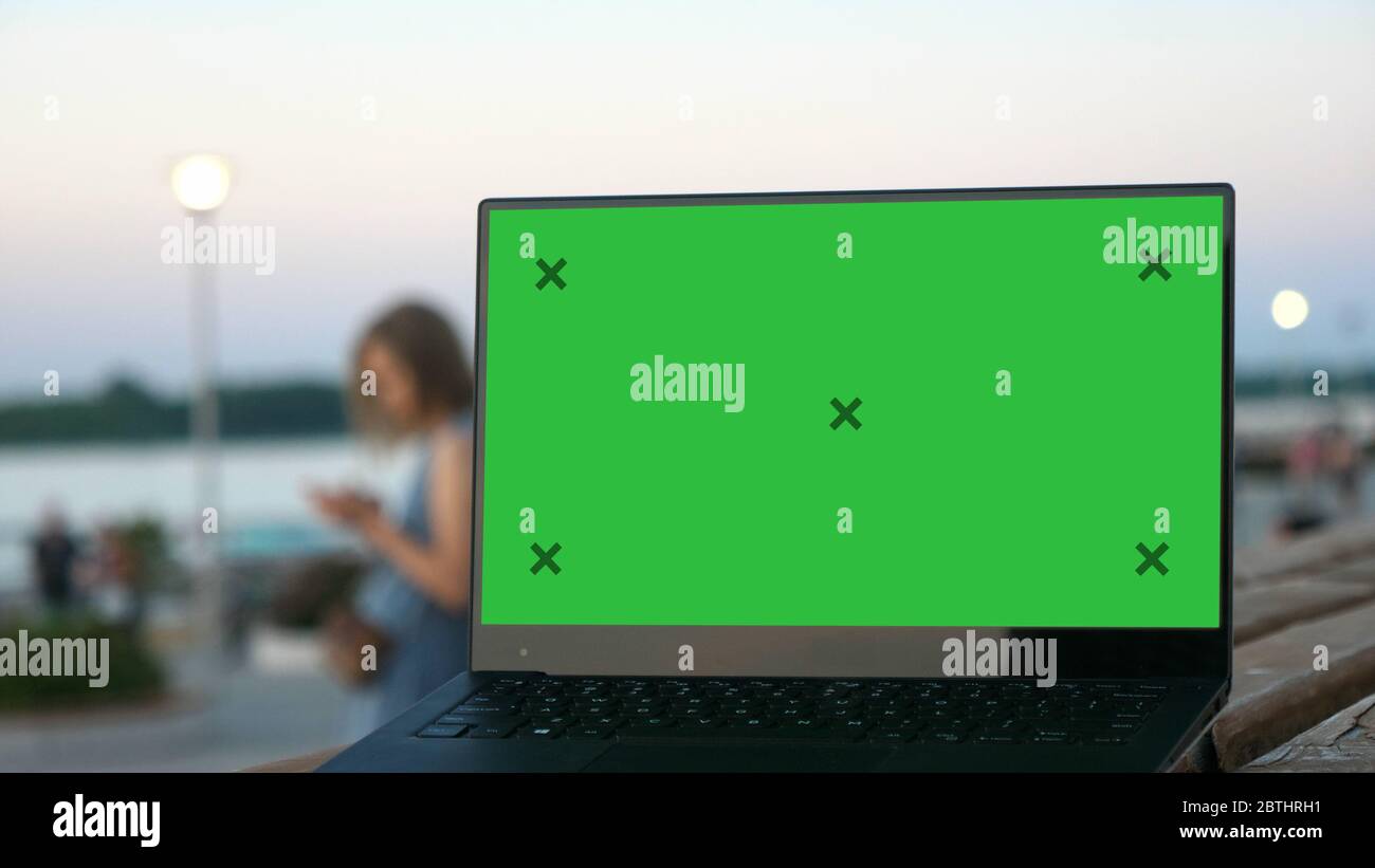 Laptop computer on street bench with green screen. Woman texting Stock ...