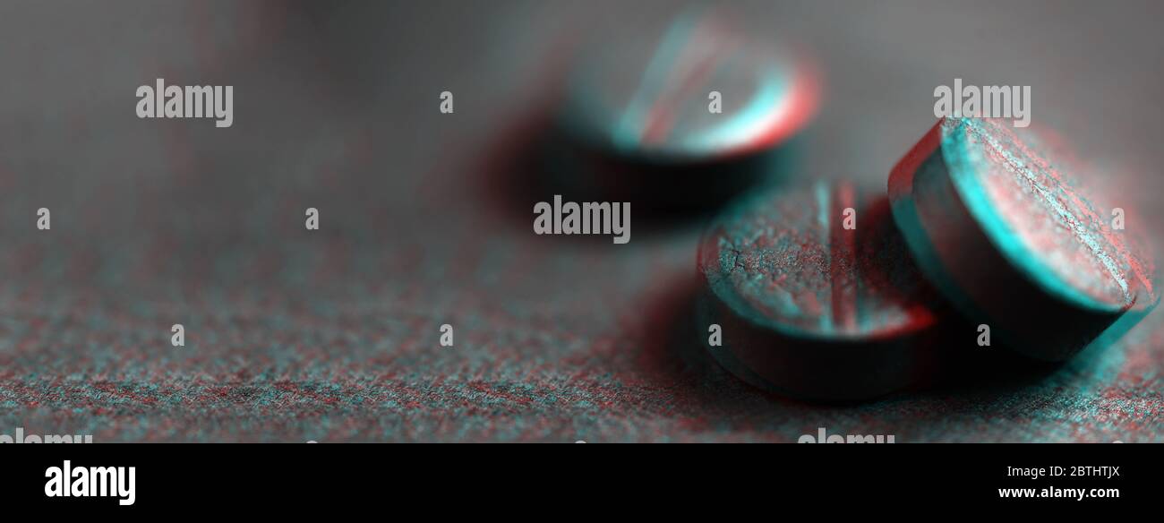 Three black activated charcoal tablets. On a black background. There's ...