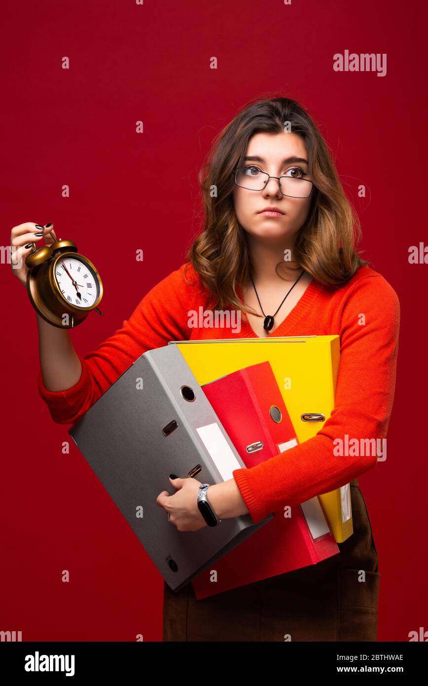 The girl in glasses carries folders, with a fright on her face on a red ...