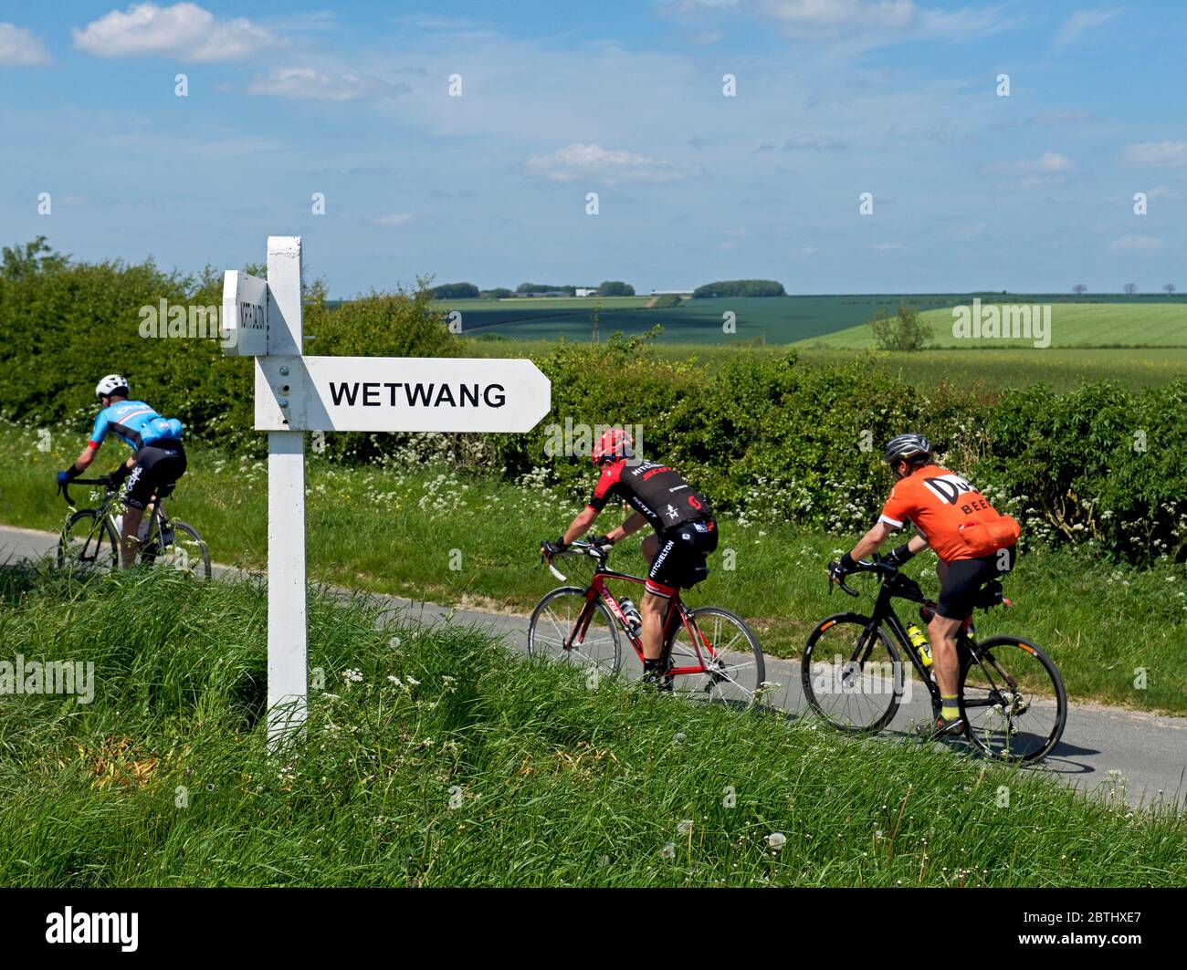 Three cyclists passing road sign - Wetwang - on minor road near Huggate ...