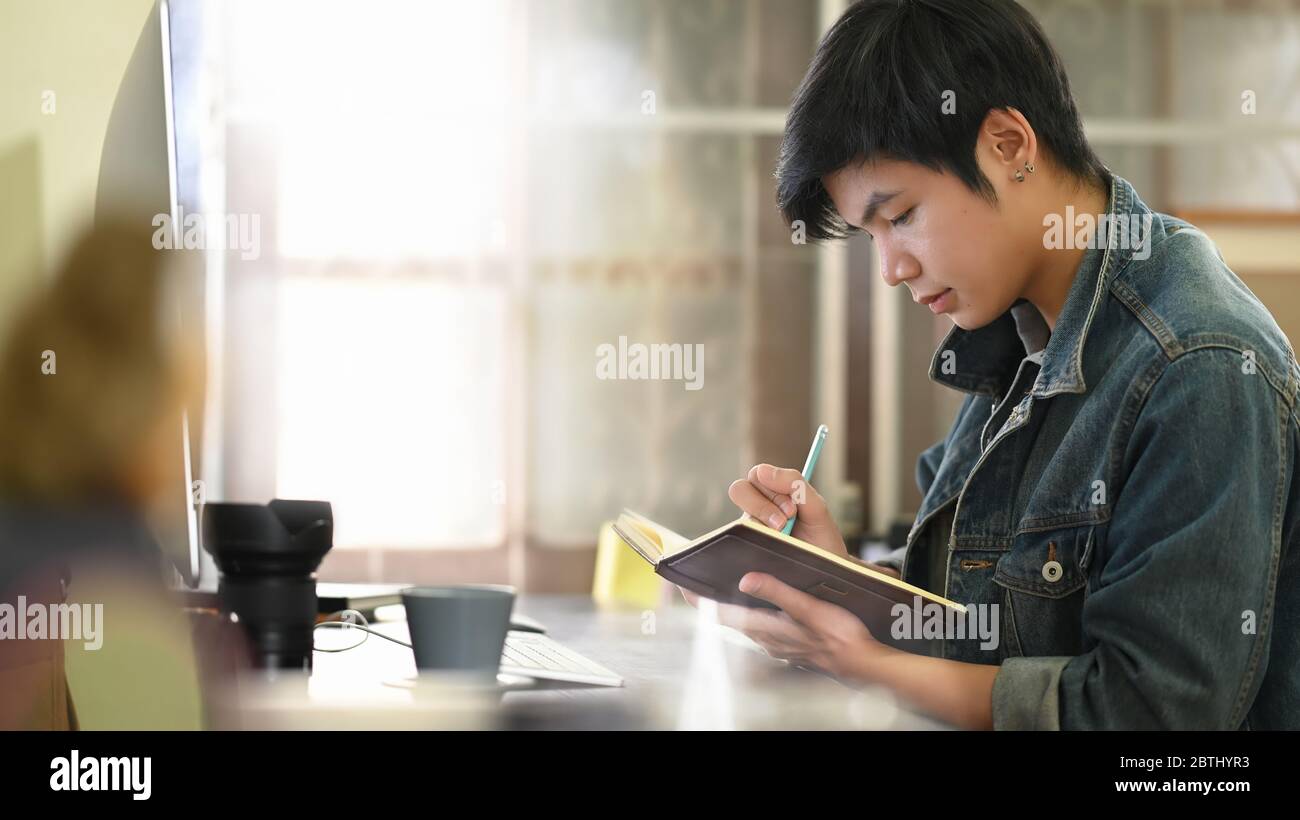 Smart man writing on notebook/taking note while sitting and relaxing at ...