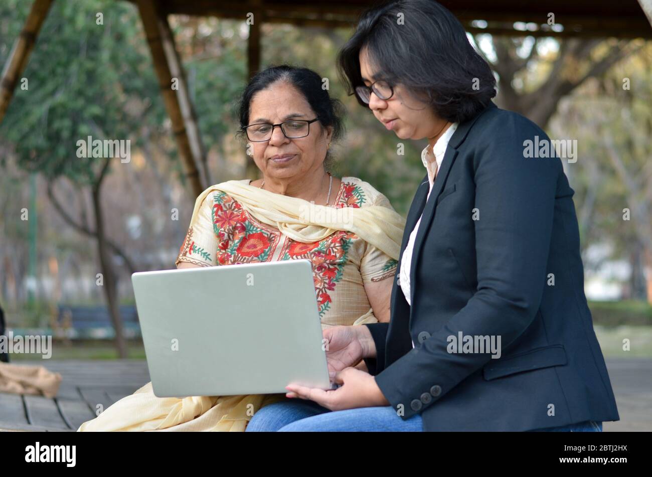Young Indian woman helping her old retired mother on a laptop sitting ...