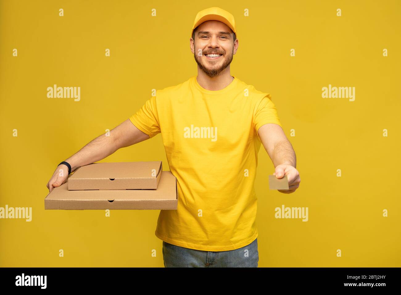 Portrait of young delivery man in yellow uniform with pizza boxes ...