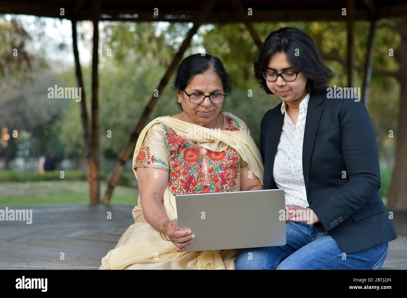 Young Indian woman helping her old retired mother on a laptop sitting ...