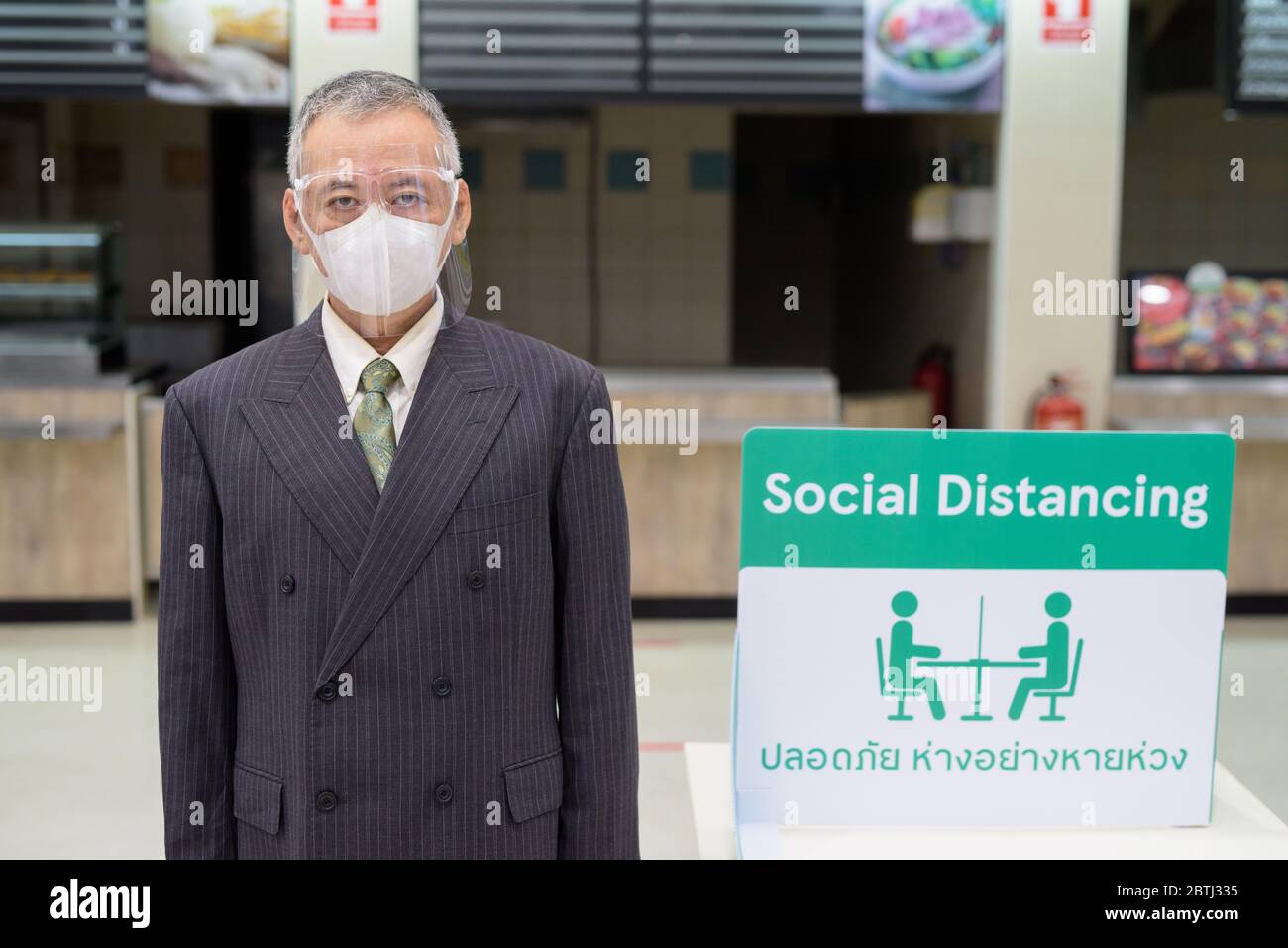 Mature Japanese businessman with mask and face shield social distancing ...