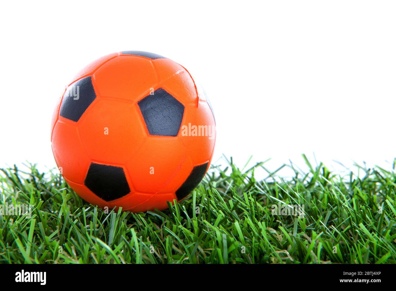 Orange soccer ball on grass over white background Stock Photo - Alamy