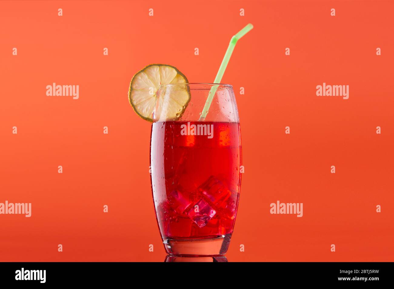 glass of cold red drink on an orange background in a nice glass and ...