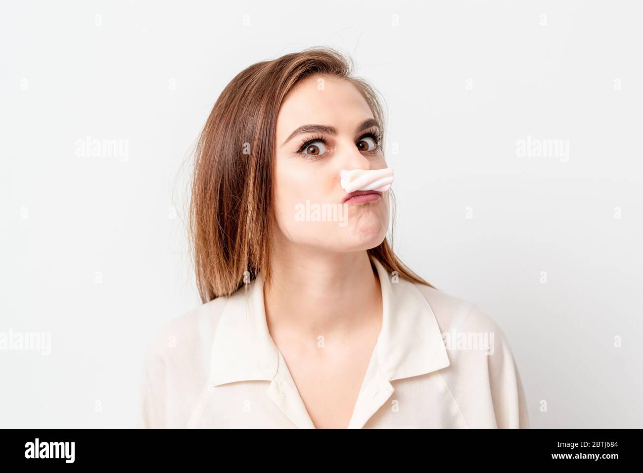 Young woman making mustache with sweet candy marshmallow on white ...