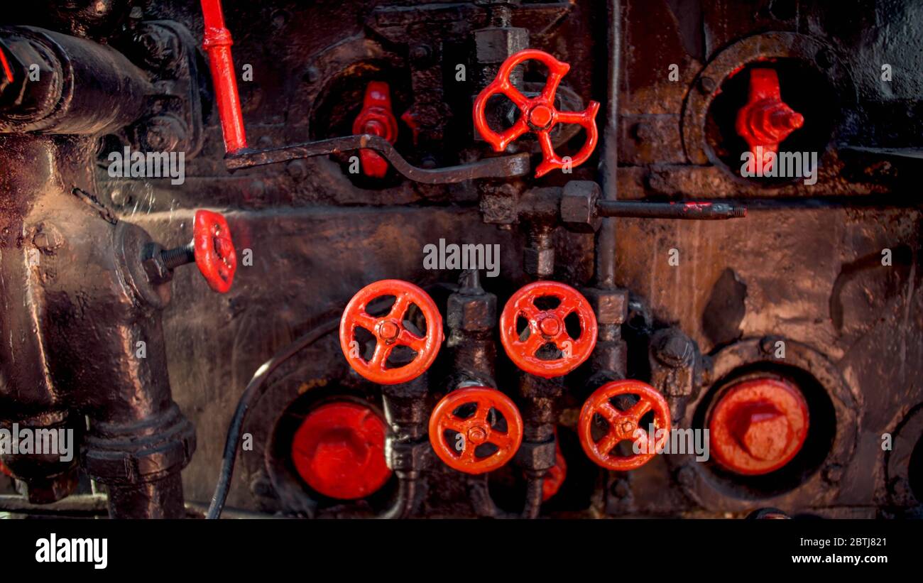 Toned photo of old rusty steam pipes and red valves on steam boiler of ...
