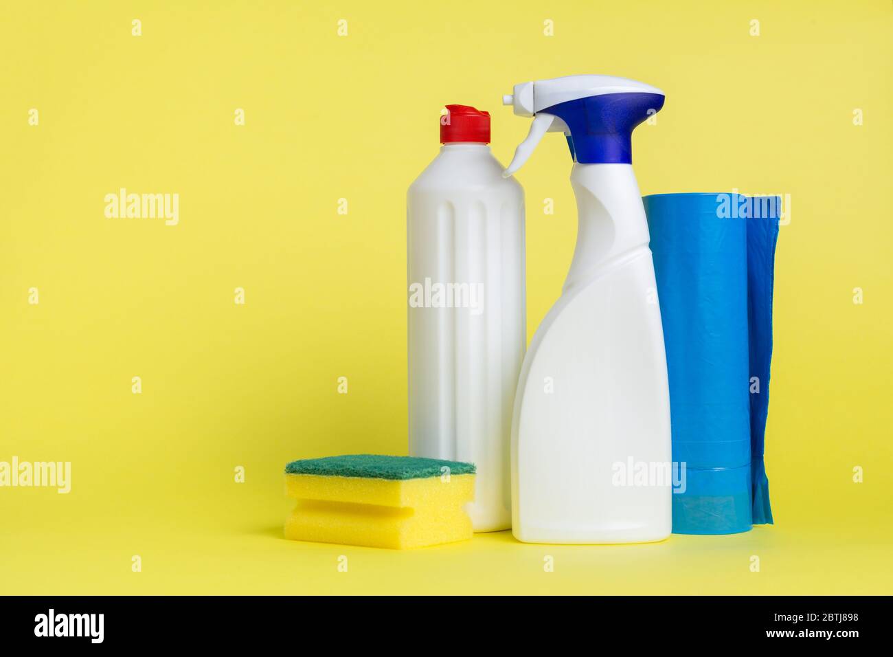 Two cans of cleaning spray with a scouring pad and garbage bags placed ...