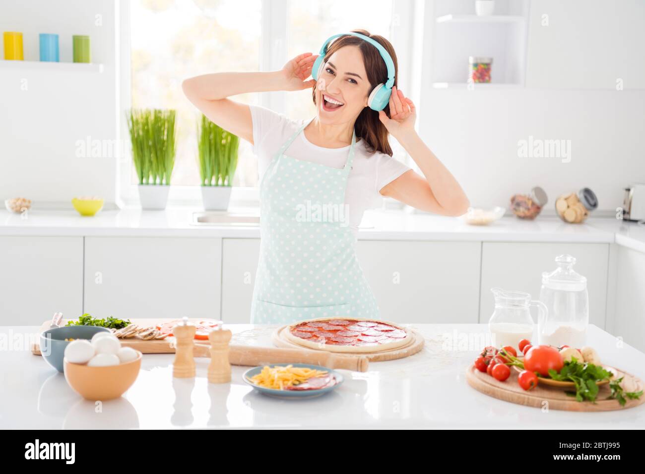 Portrait of cheerful funky girl enjoy cooking pizza while listen rhythm ...