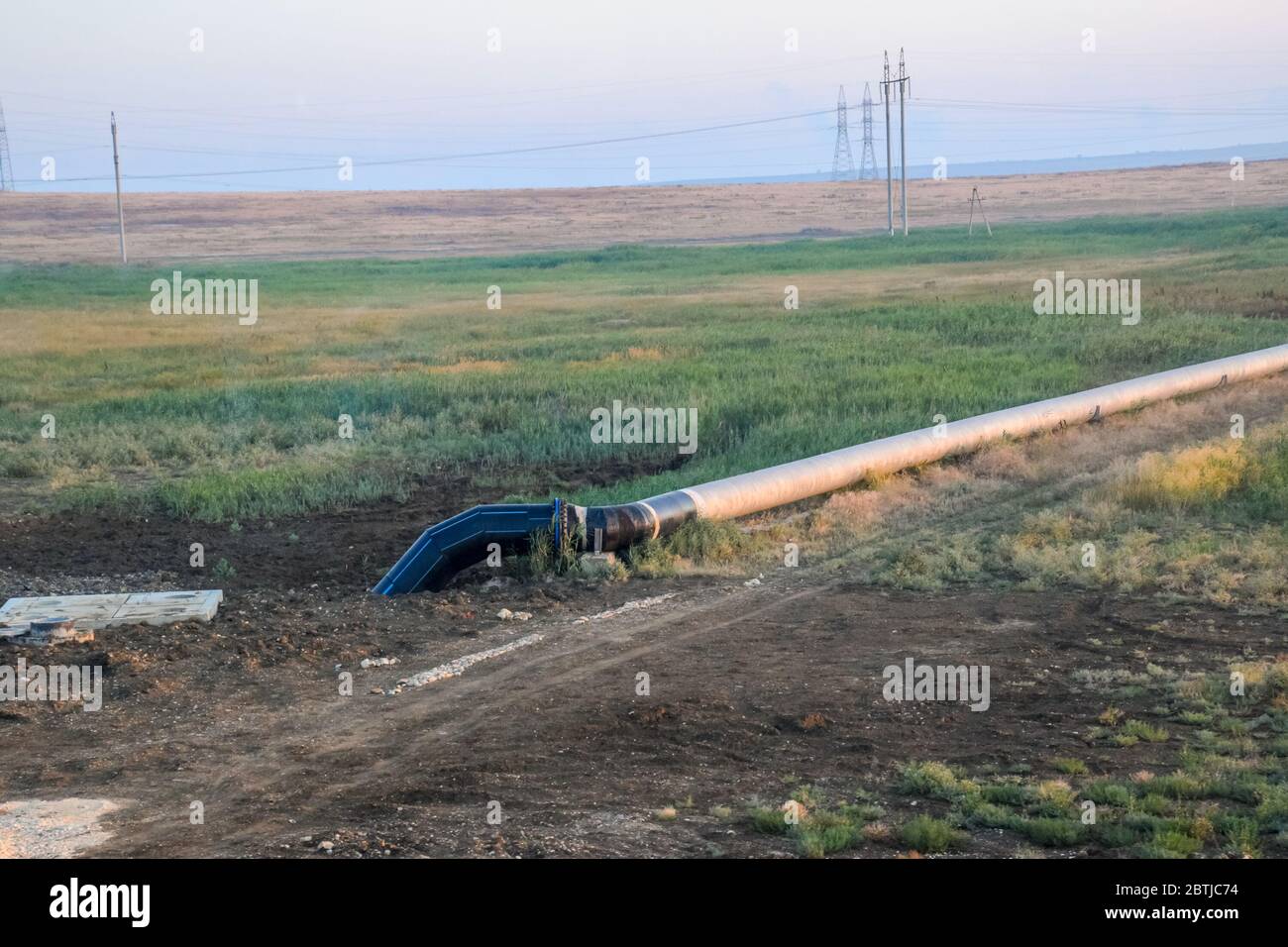 A gas pipeline in the field. The pipe goes on the surface and goes ...