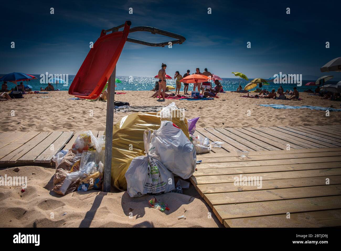 Overflowing trash bin surrounded by garbage on Comporta beach, Portugal ...