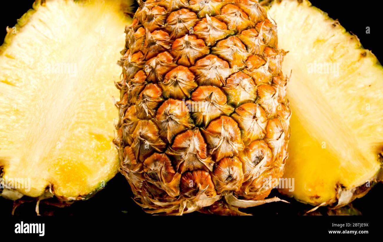 Closeup image of fresh cut pineapple cut in halves over black ...