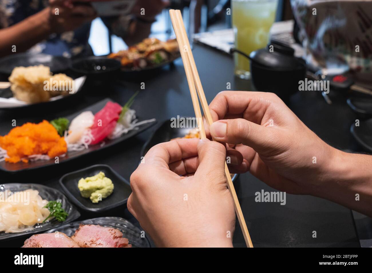 Hand using chopsticks pick Sushi and Sashimi rolls. Fresh made Sushi ...