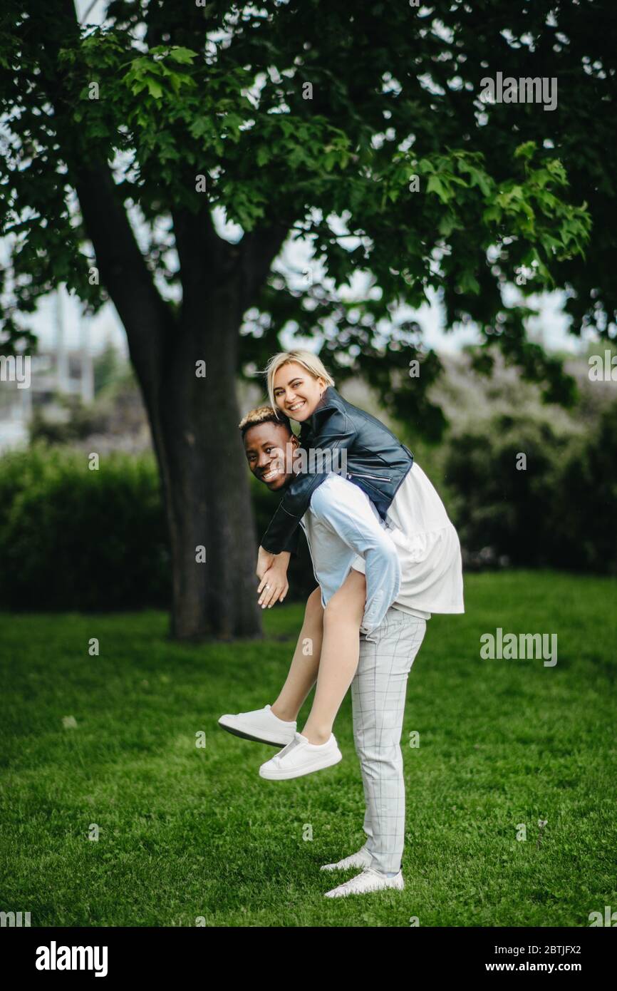 Young interracial couple has a fun, plays and laughs in park. The ...