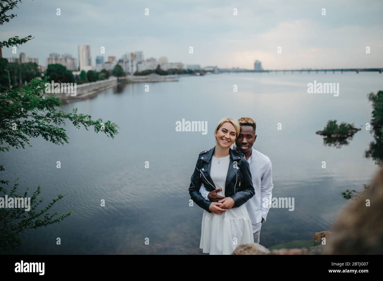 Interracial couple stands against background of river and city. Concept ...