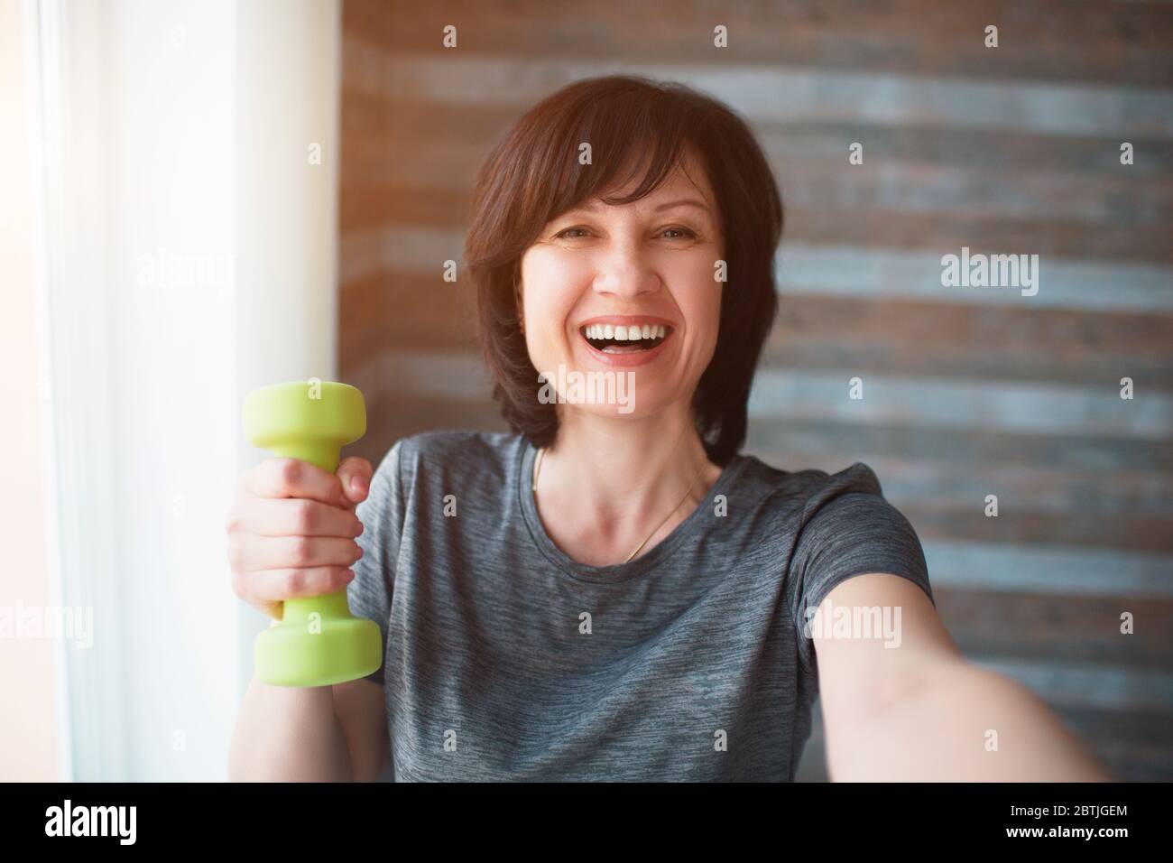 Adult fit slim woman has workout at home. Cheerful positive happy adult ...