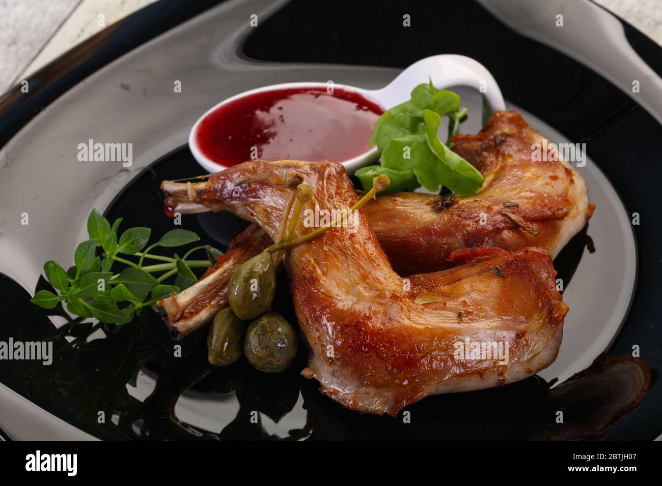 Roasted rabbit legs with cowberry sauce Stock Photo - Alamy