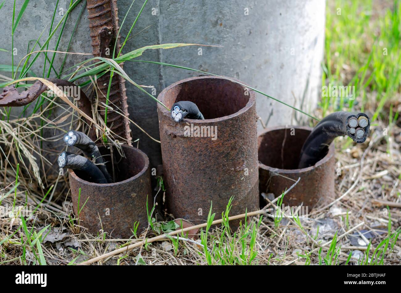 Severed underground electric power cable. Metal pipes stick out of the ...