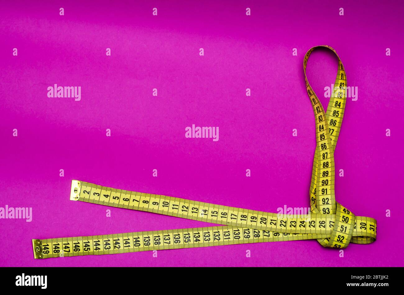 Yellow tailor measuring tape on a lilac background. Twisted measuring ...