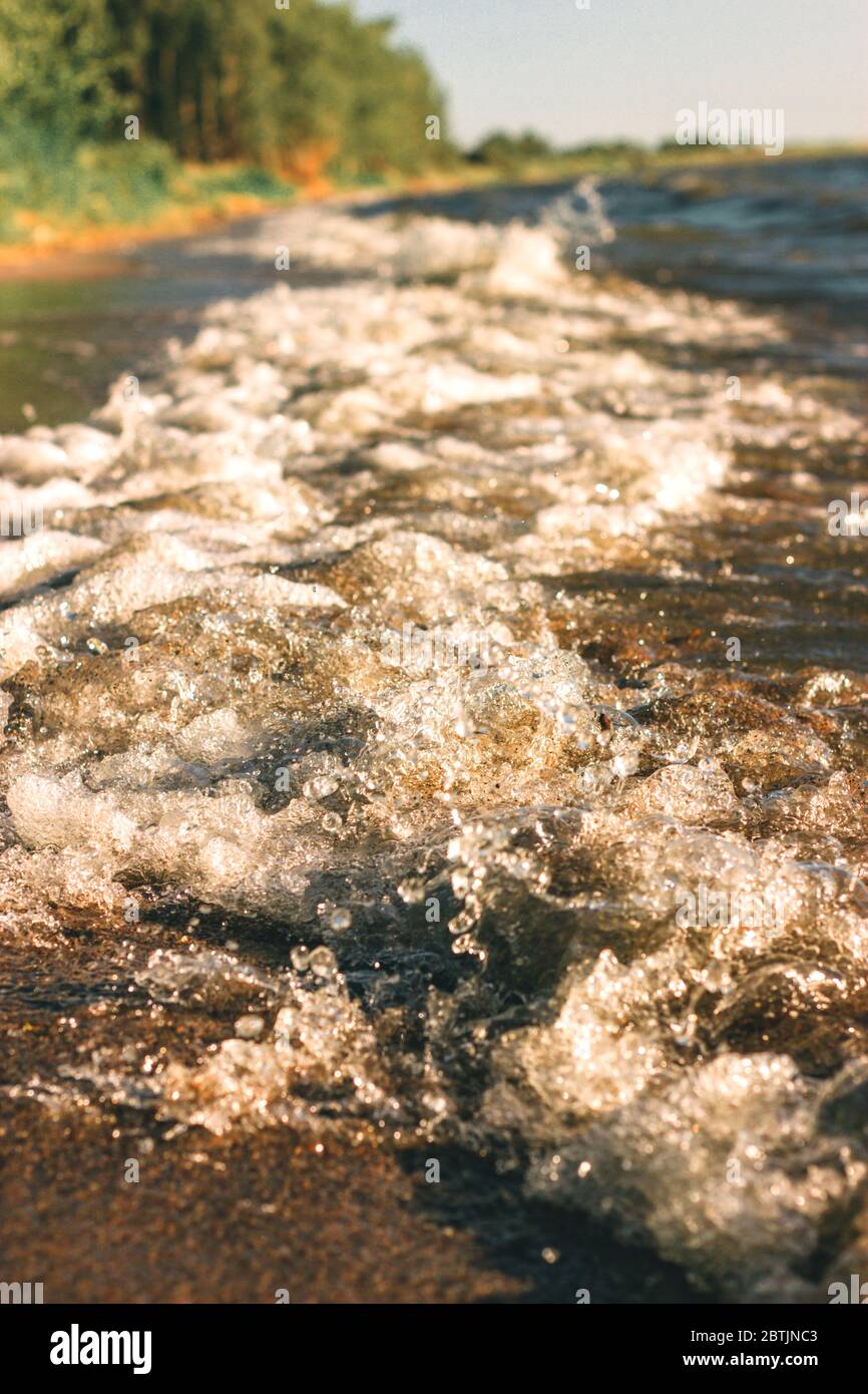 Wave with spray on the sandy beach Stock Photo - Alamy