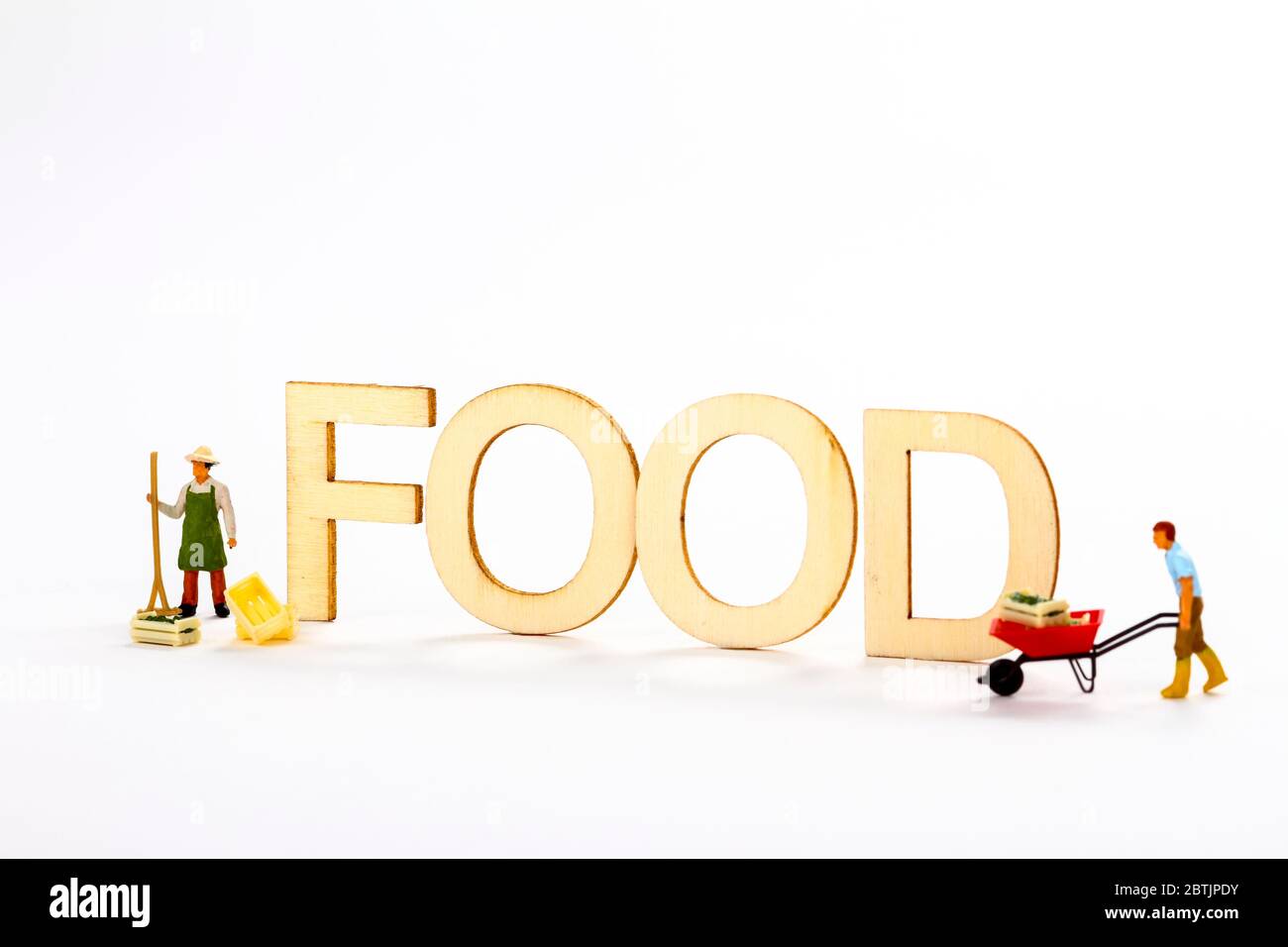 Miniature figure people with a wheelbarrow full of food next to a ...