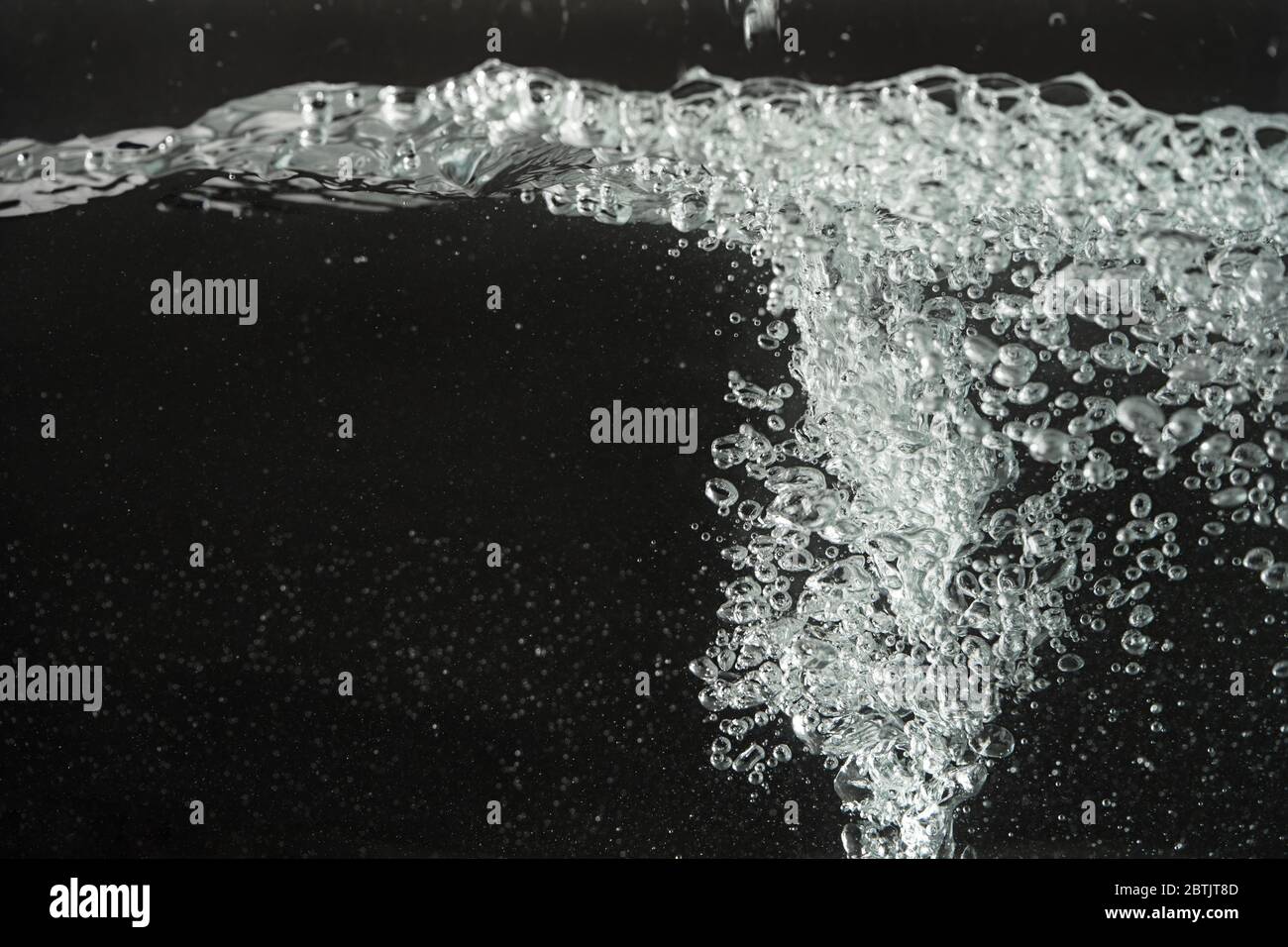 Water splashing as it's poured into aquarium tank, black background ...