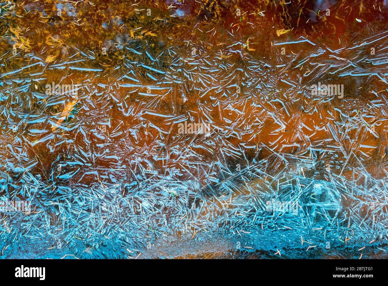 A frozen puddle with a blue pattern on the ice Stock Photo - Alamy