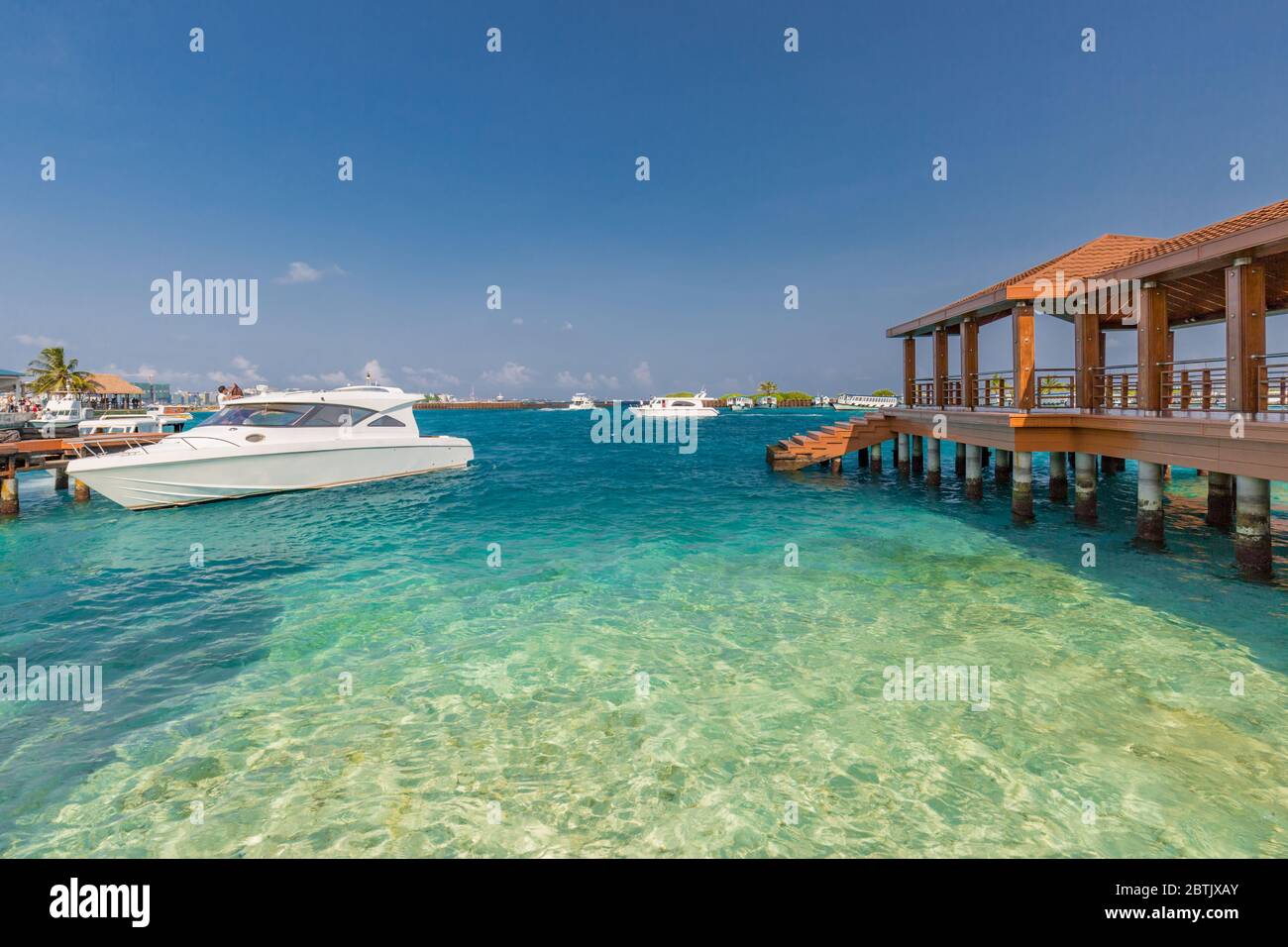 Maldives airport dock and boats picking up tourists in blue lagoon next ...